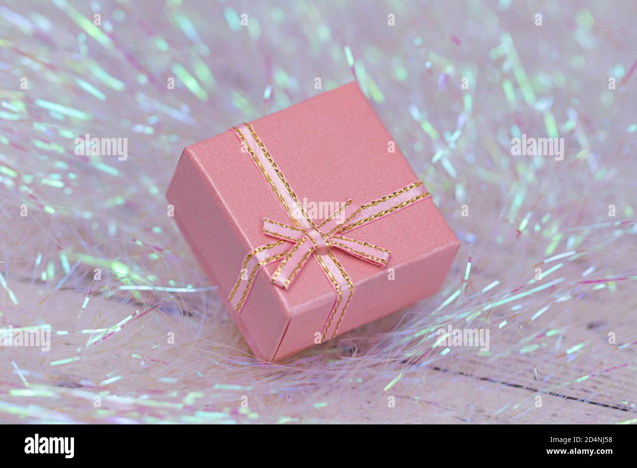 Pink gift box with golden bow lies on sparkling background. Gift ...