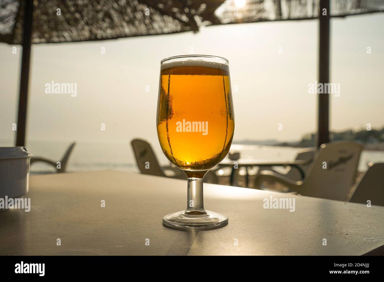 A glass of beer on a table served in a beach restaurant, with ...