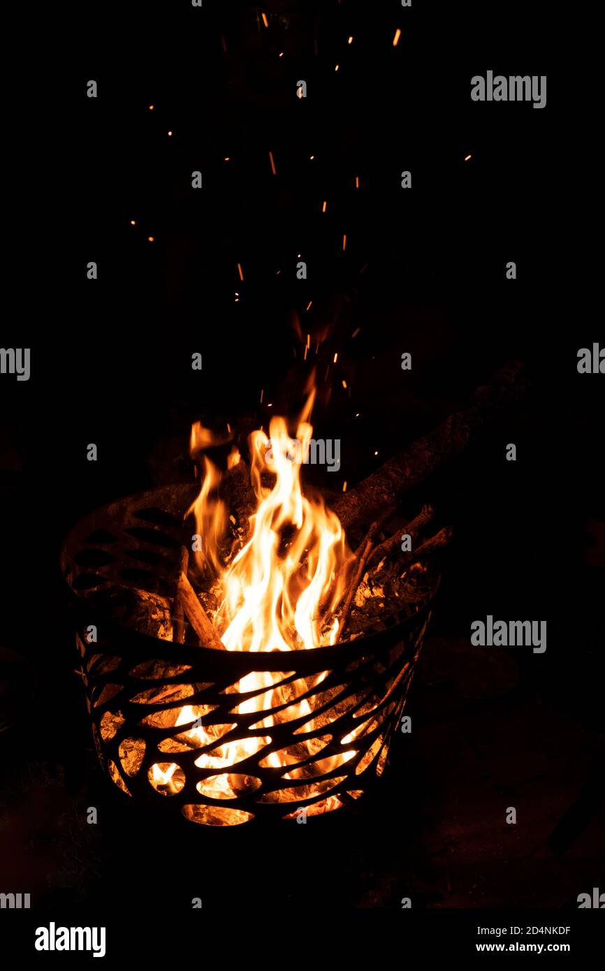 Fire pit with flames at nighttime sparks off logs Stock Photo - Alamy