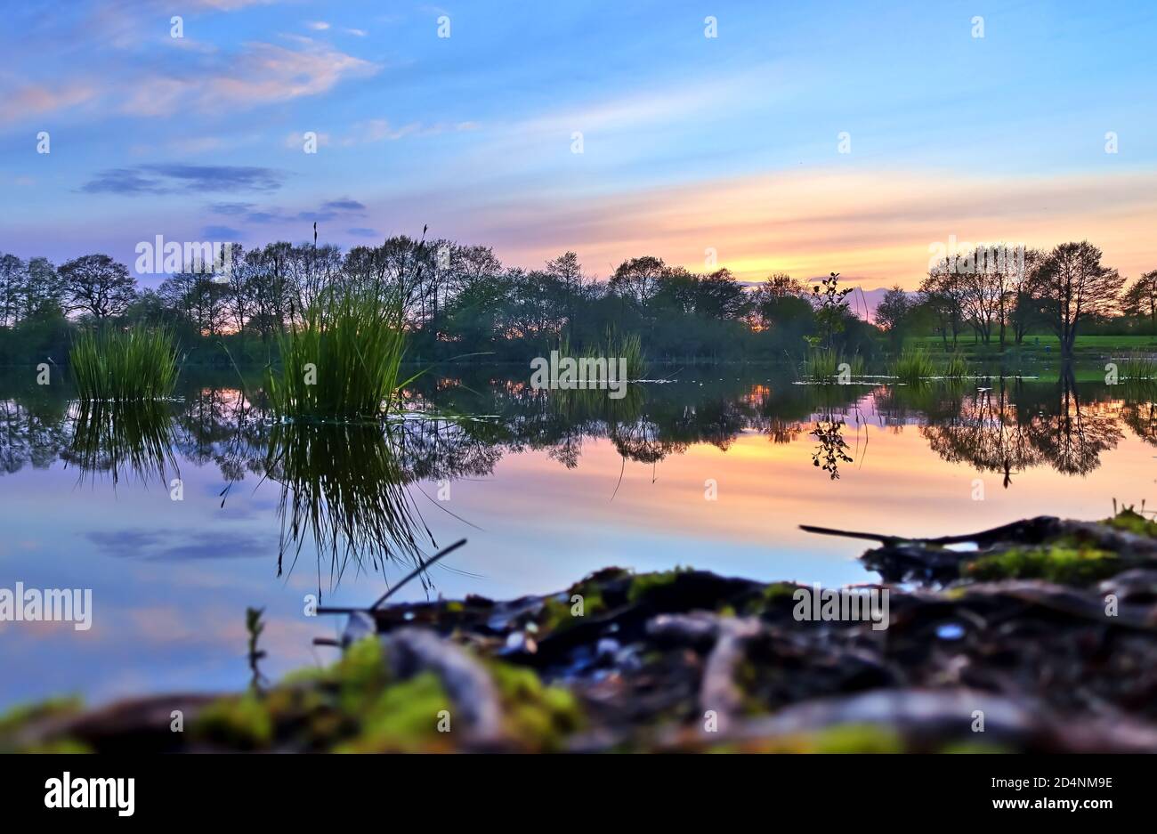 Beautiful sunset landscape at a lake with a reflective water surface ...
