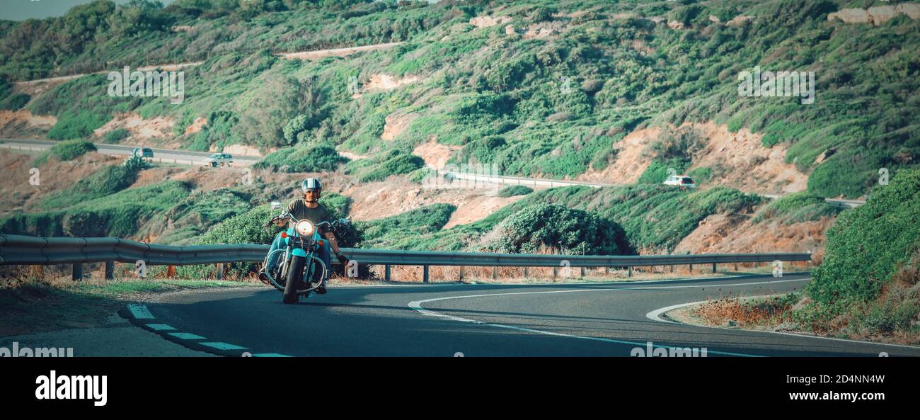 Panoramic view of a biker on a classic motorcycle greeting while riding ...