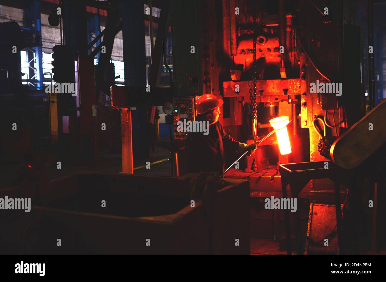 Blacksmith processes the red hot iron under a huge press. Metal forging ...