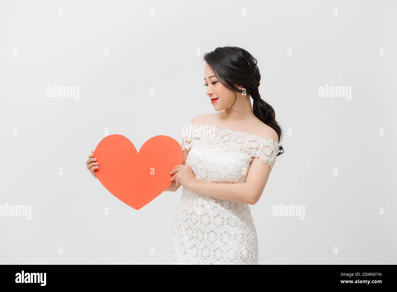 Attractive Young Asian Woman Holding Red Love Shape And Standing Over