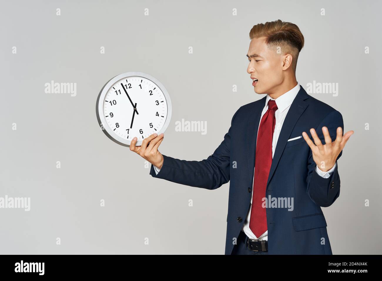 Upset man with a clock in his hands at work Stock Photo - Alamy