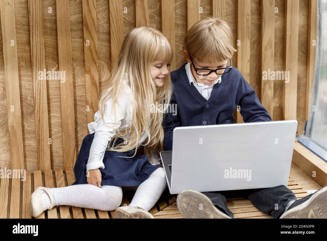 Two children are sitting at the window of the house and are looking at ...