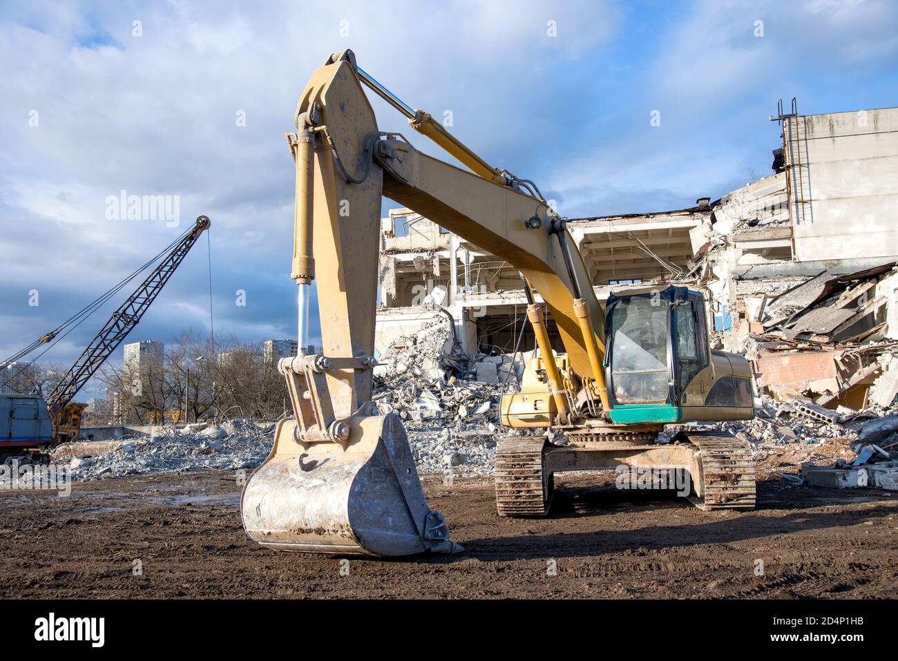 Yellow excavator with bucket at demolition of tall building. Hydraulic ...