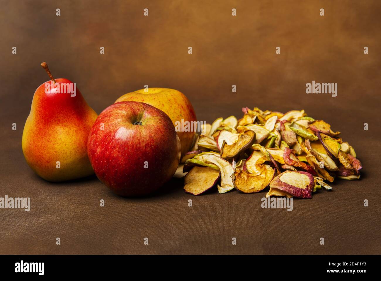 Pile of dried apples together with two whole apples and one pear. Still ...