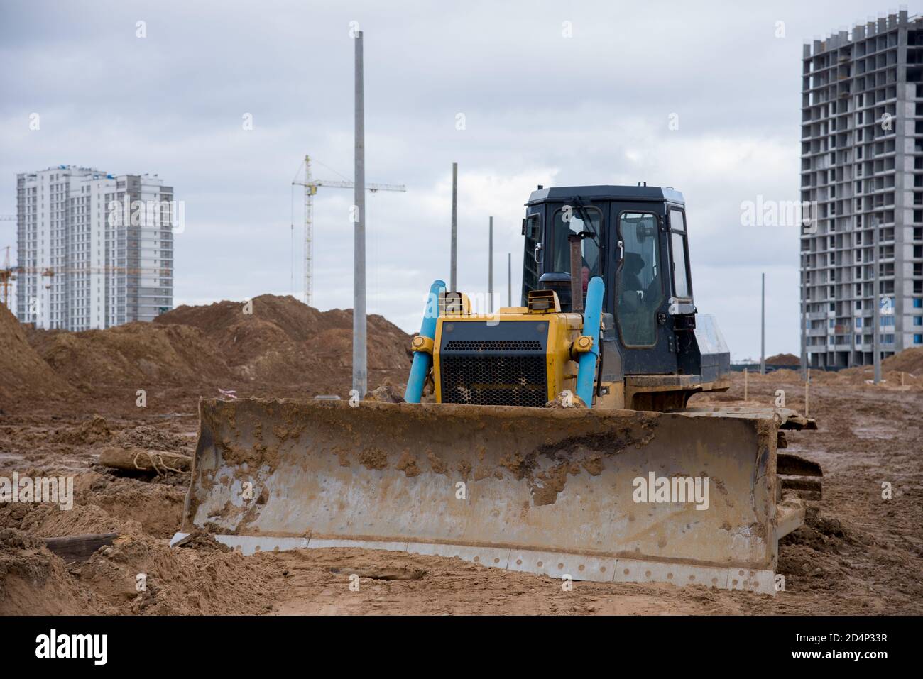 Dozer during land clearing and foundation digging against tower cranes ...