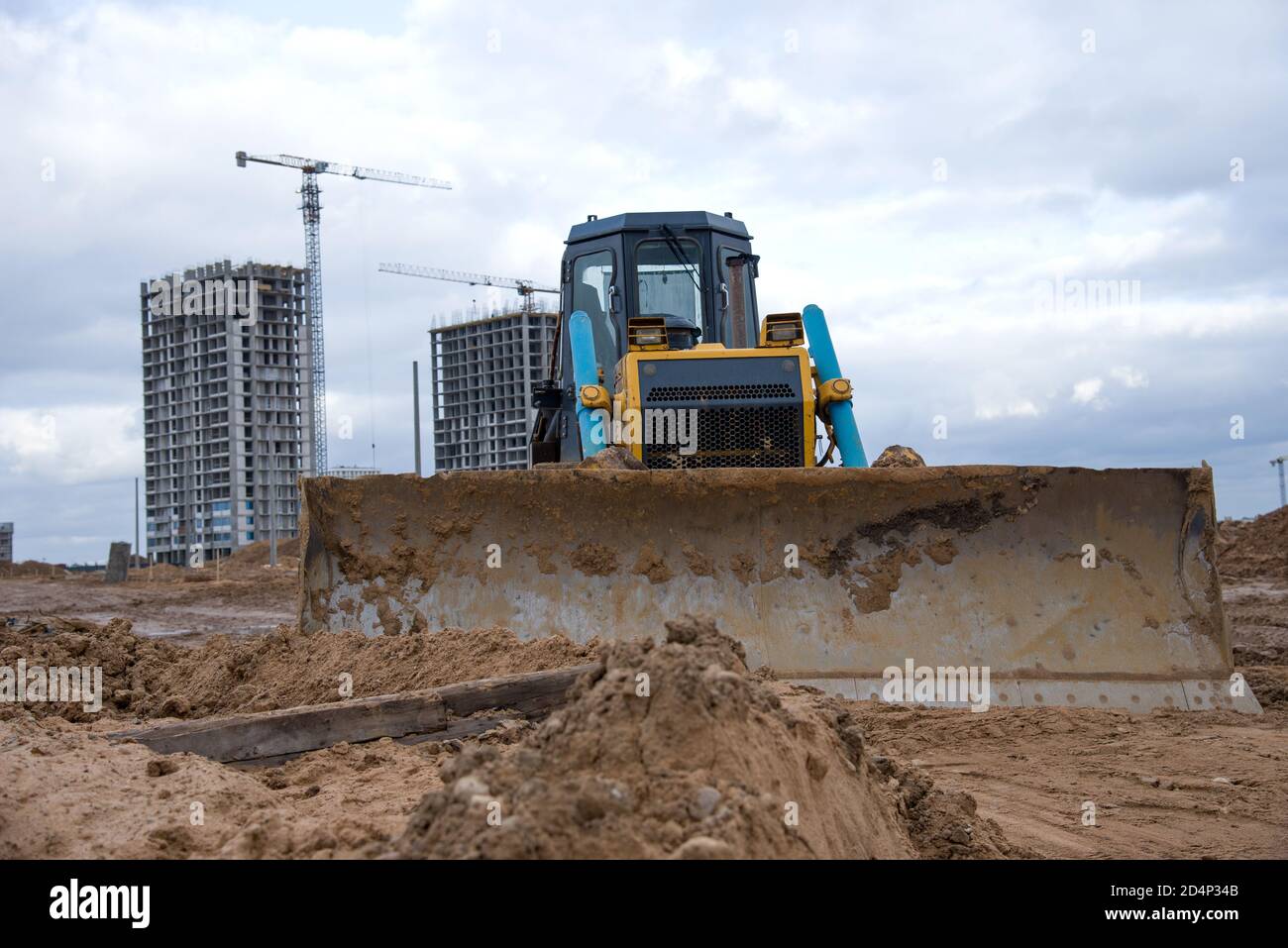 Dozer during land clearing and foundation digging against tower cranes ...