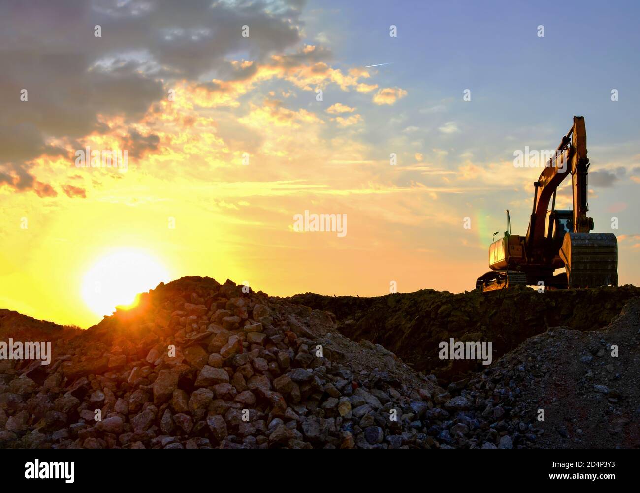 Excavator in a mining quarry at sunset. Crushing concrete and gravel ...