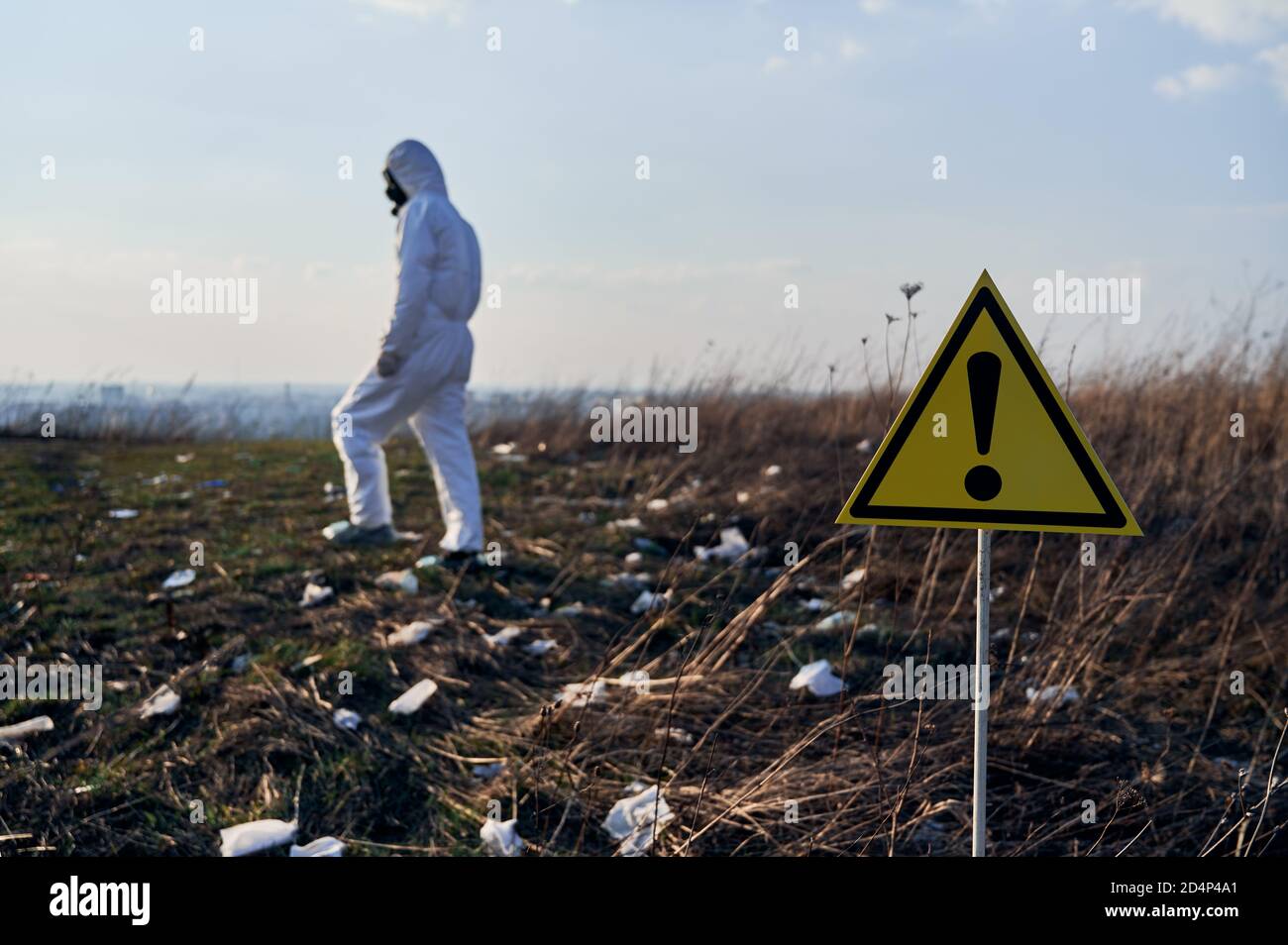 Focus on warning sign. Back view of male ecologist in protective suit ...