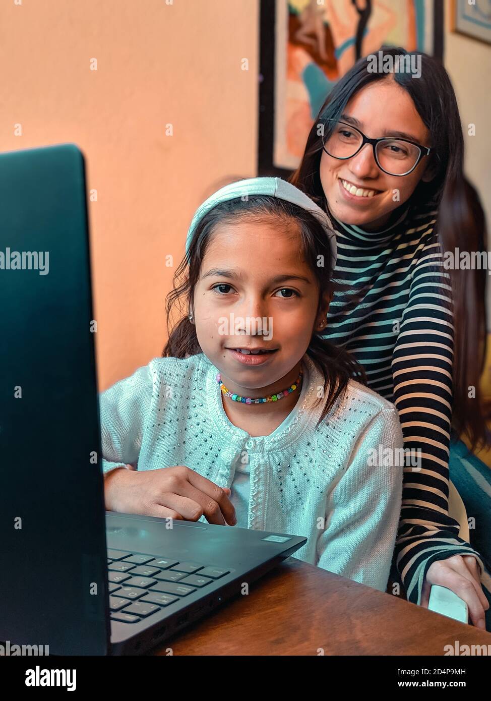 Elder sister helping her little sister with her homework on the laptop ...