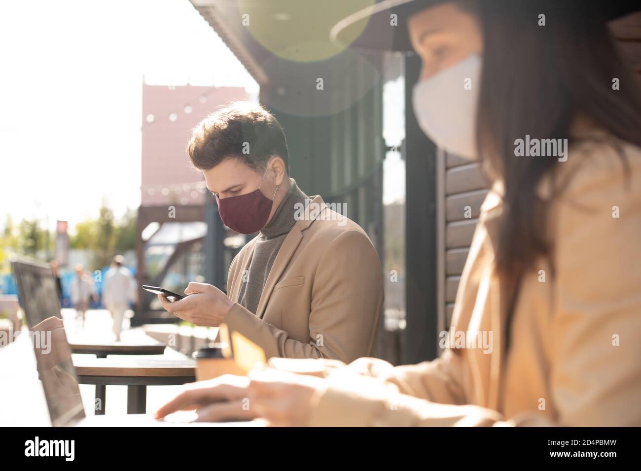 Side view of young elegant man in protective mask scrolling in ...