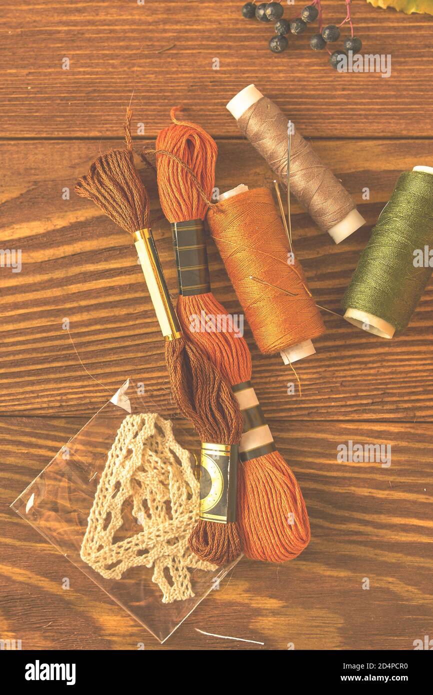 Floss yarn, laces, colored balls of thread and needles on a wooden ...