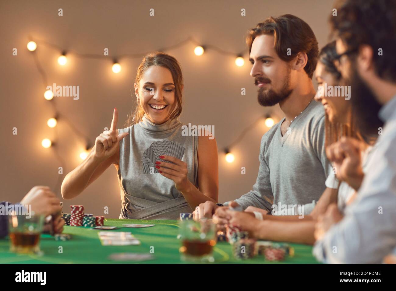 Happy young woman holds up finger as she has lucky hand in poker game ...