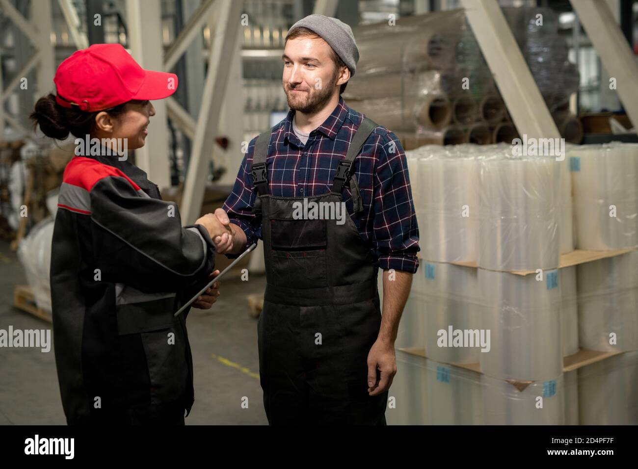 Happy young male engineer in overalls and checkered shirt shaking ...