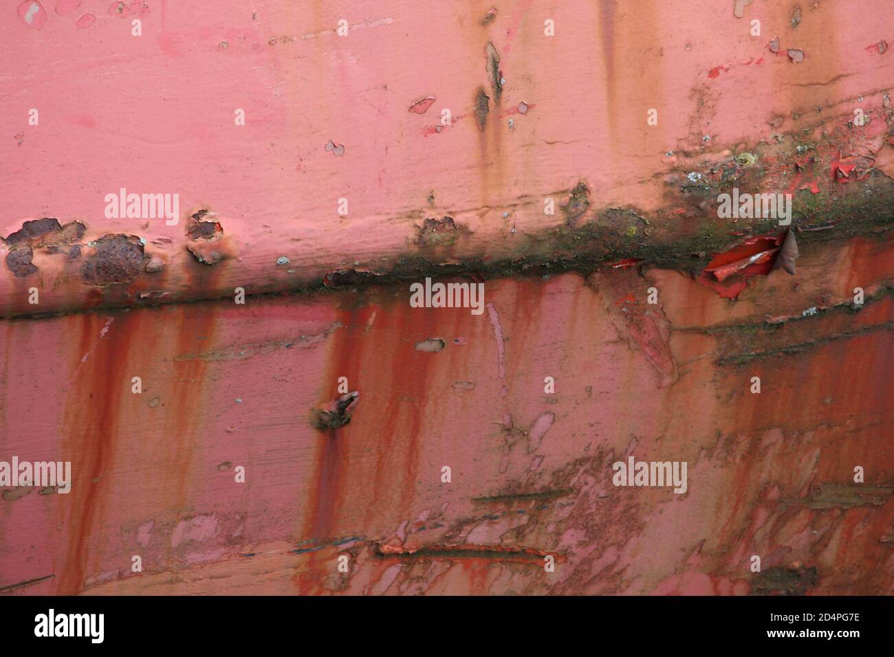 A close up photograph of rust and dirty old red paint on the body of a ...