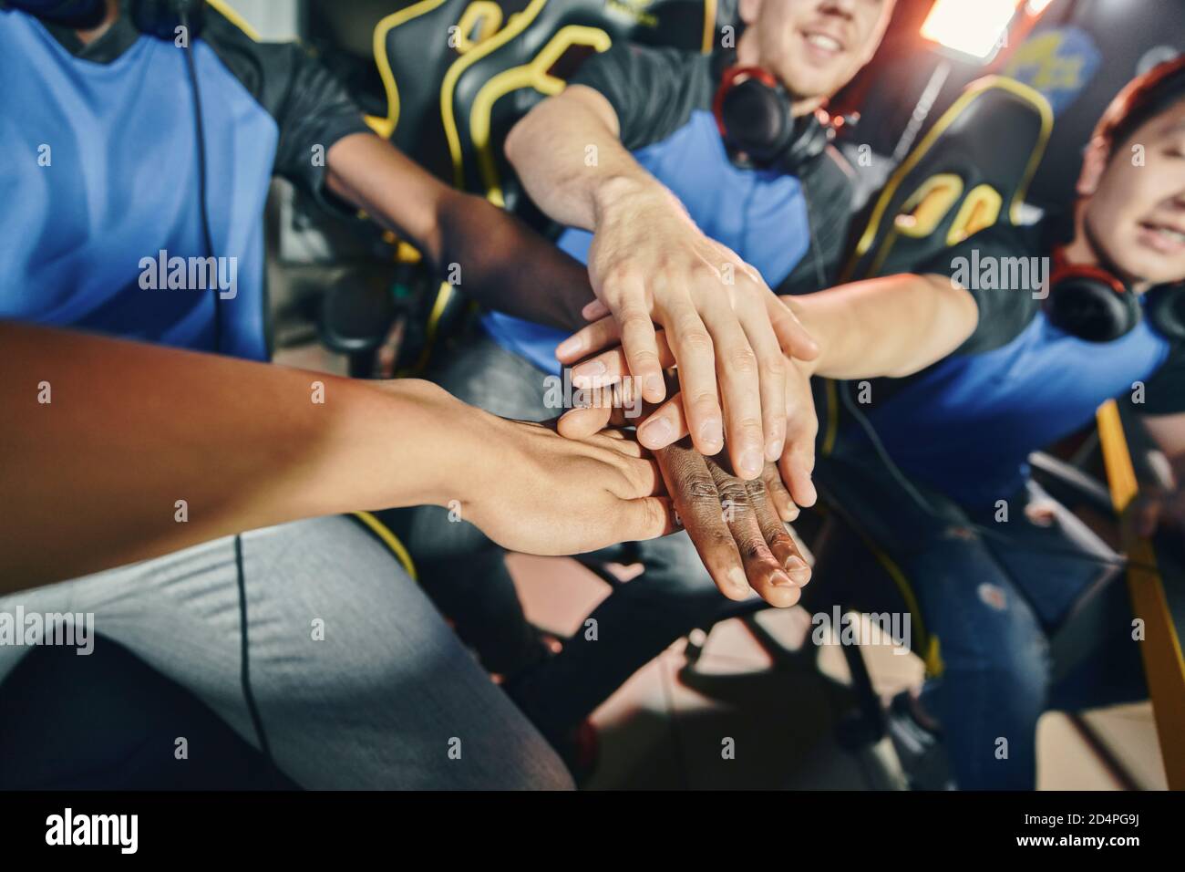 Team of professional cyber sport gamers putting hands together before ...