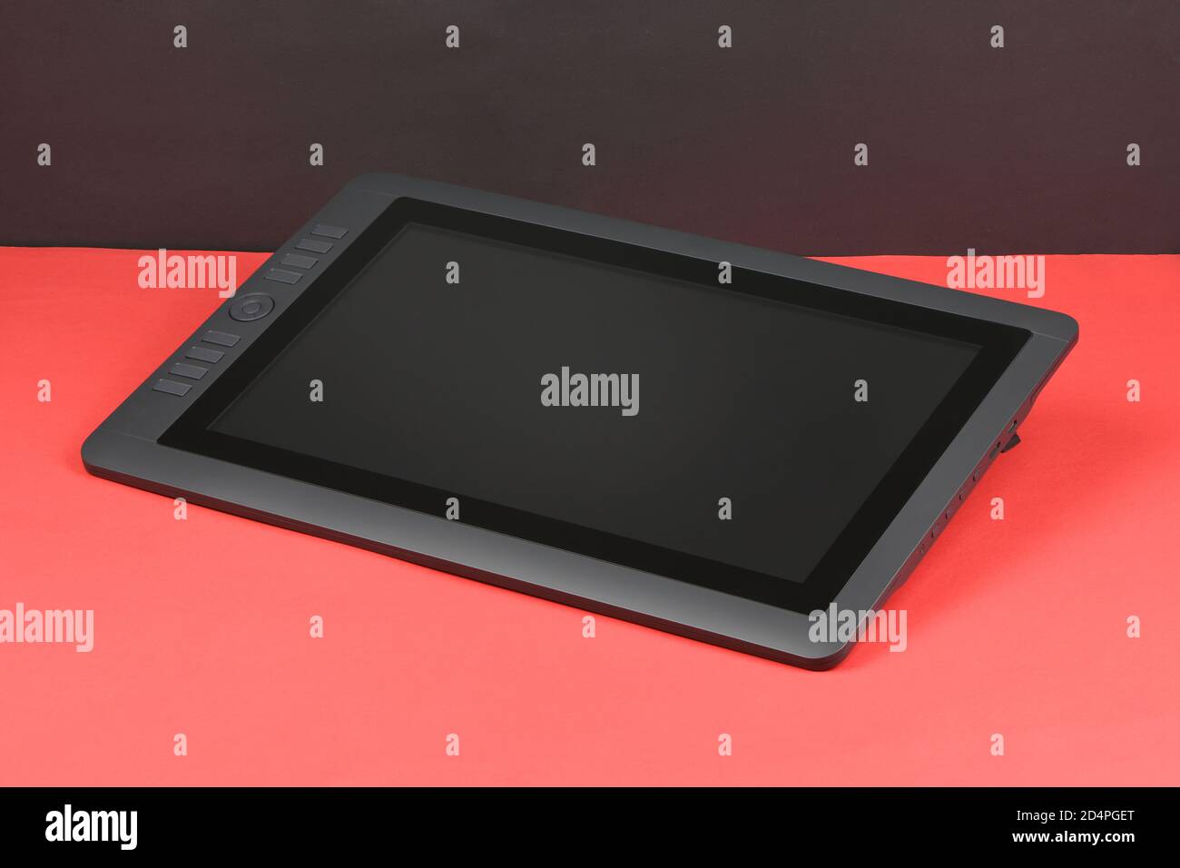 Graphic monitor on red color table. Black tablet computer with blank ...