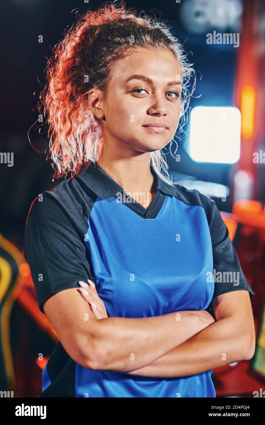 Portrait of a young mixed race female cyber sport gamer keeping arms ...