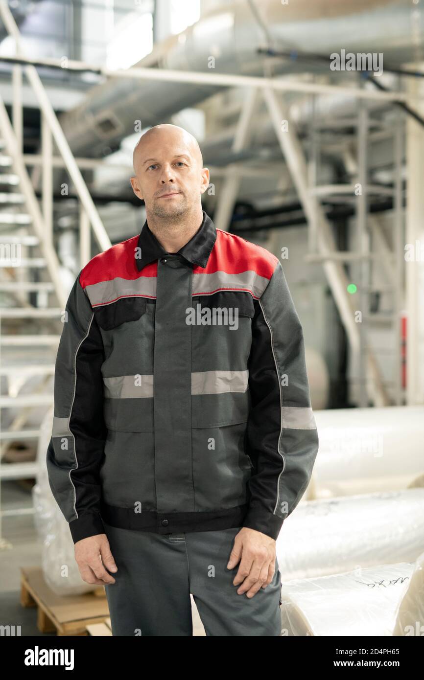 Bald mature male engineer in workwear standing inside polymer ...