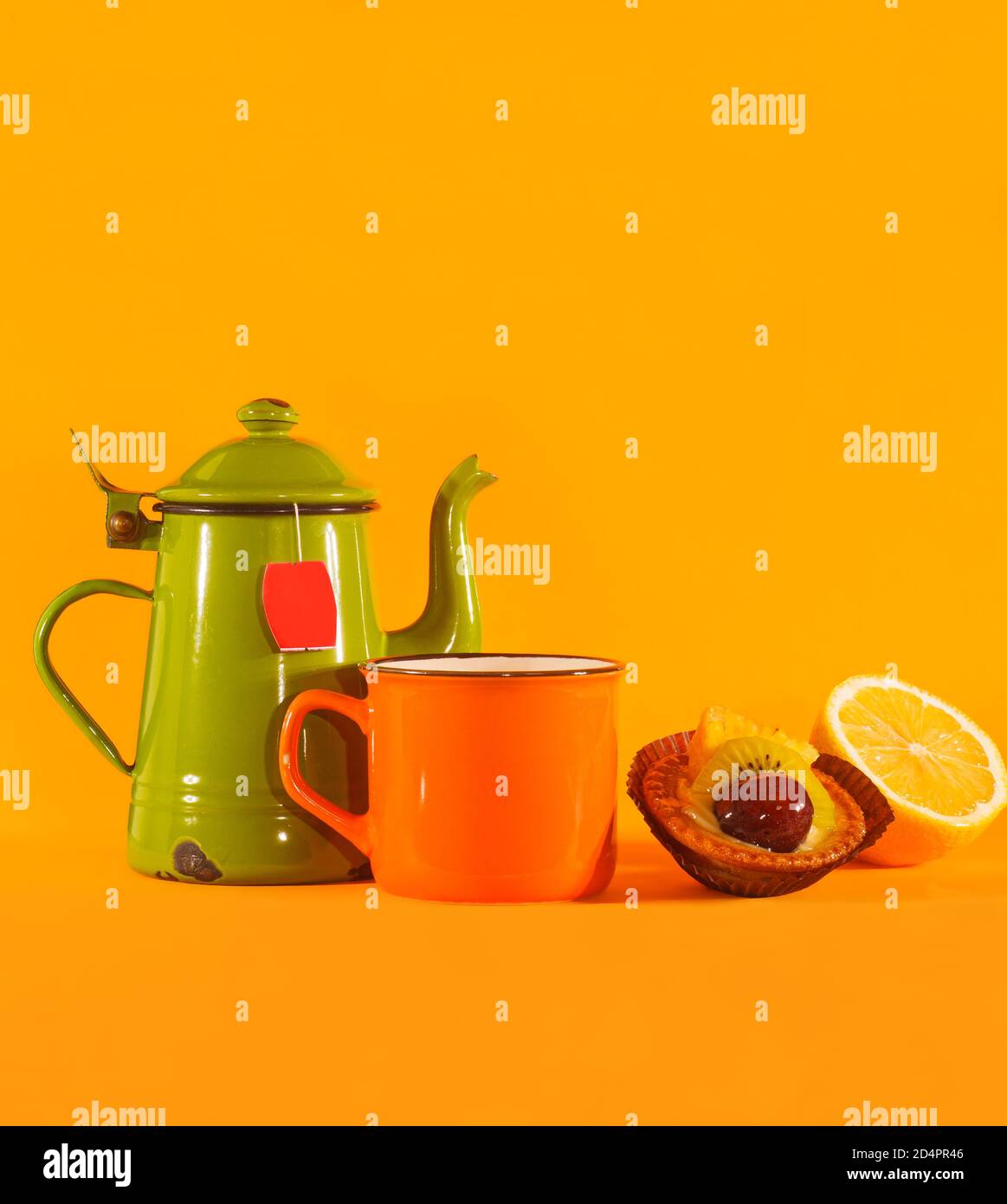 Set of vintage teacup, orange cup, lemon and pastry on orange ...