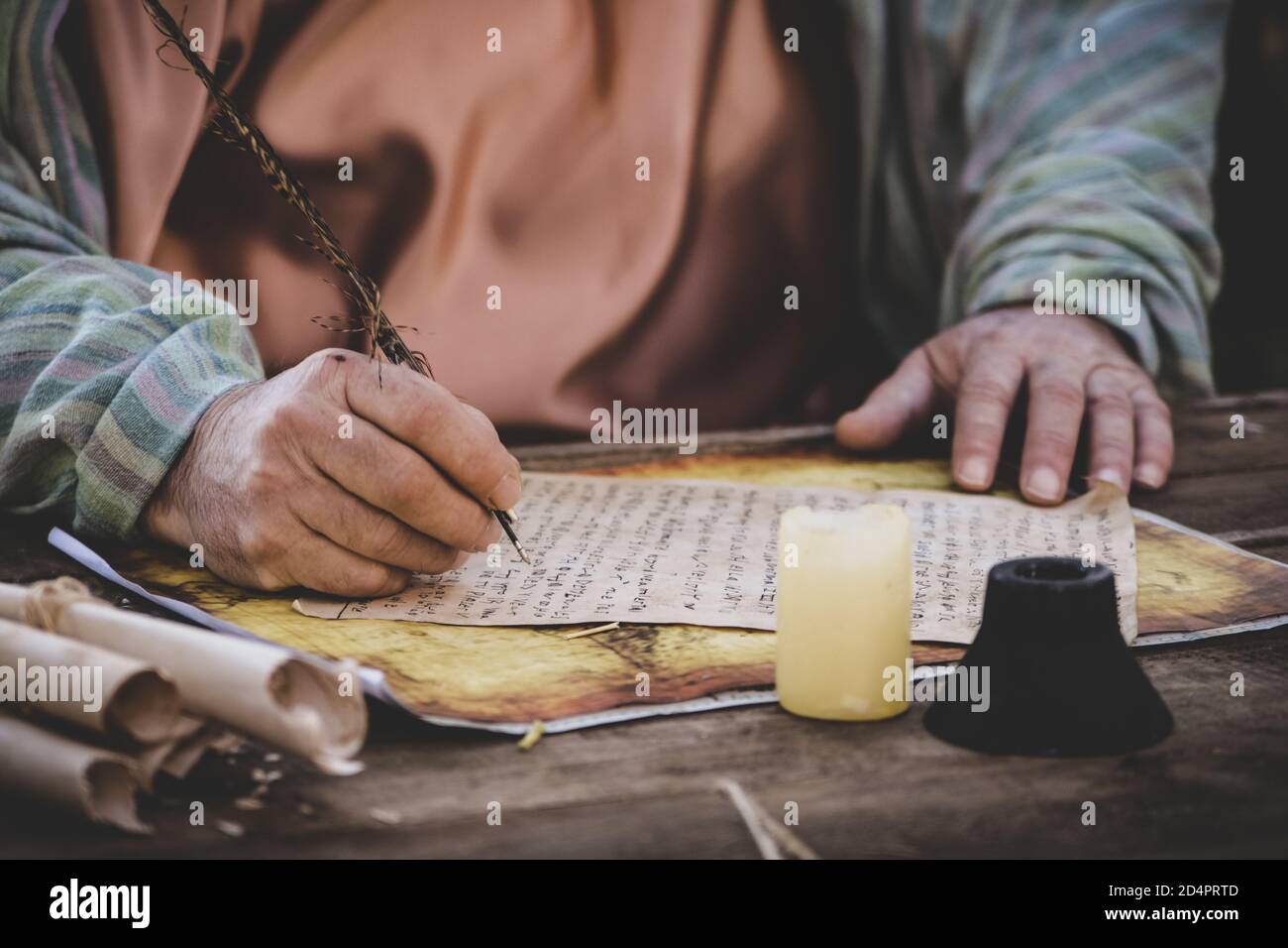 Closeup of man in a robe writing on old paper scrolls Stock Photo - Alamy