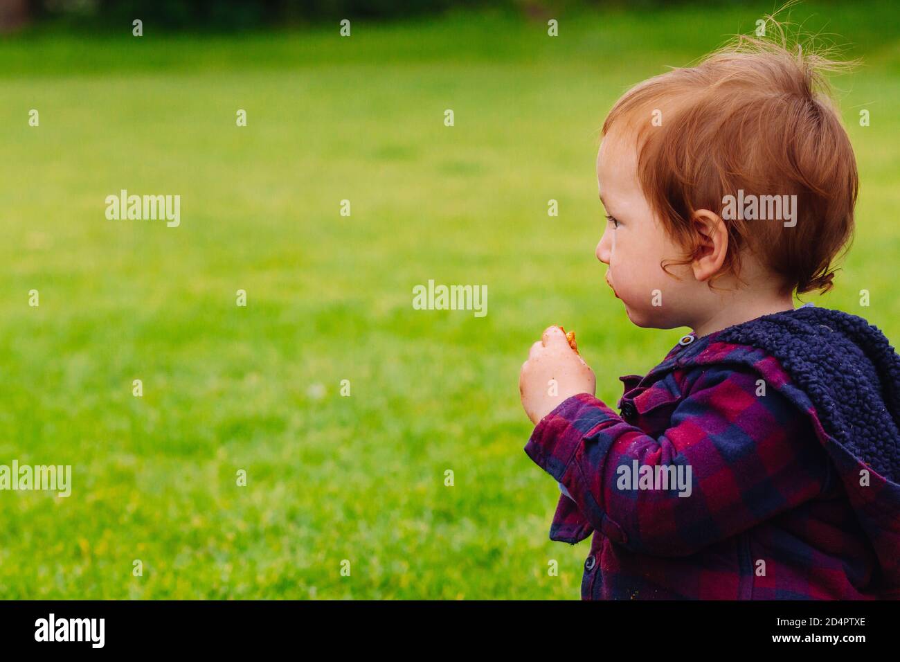Toddler enjoying a snack outside Stock Photo - Alamy