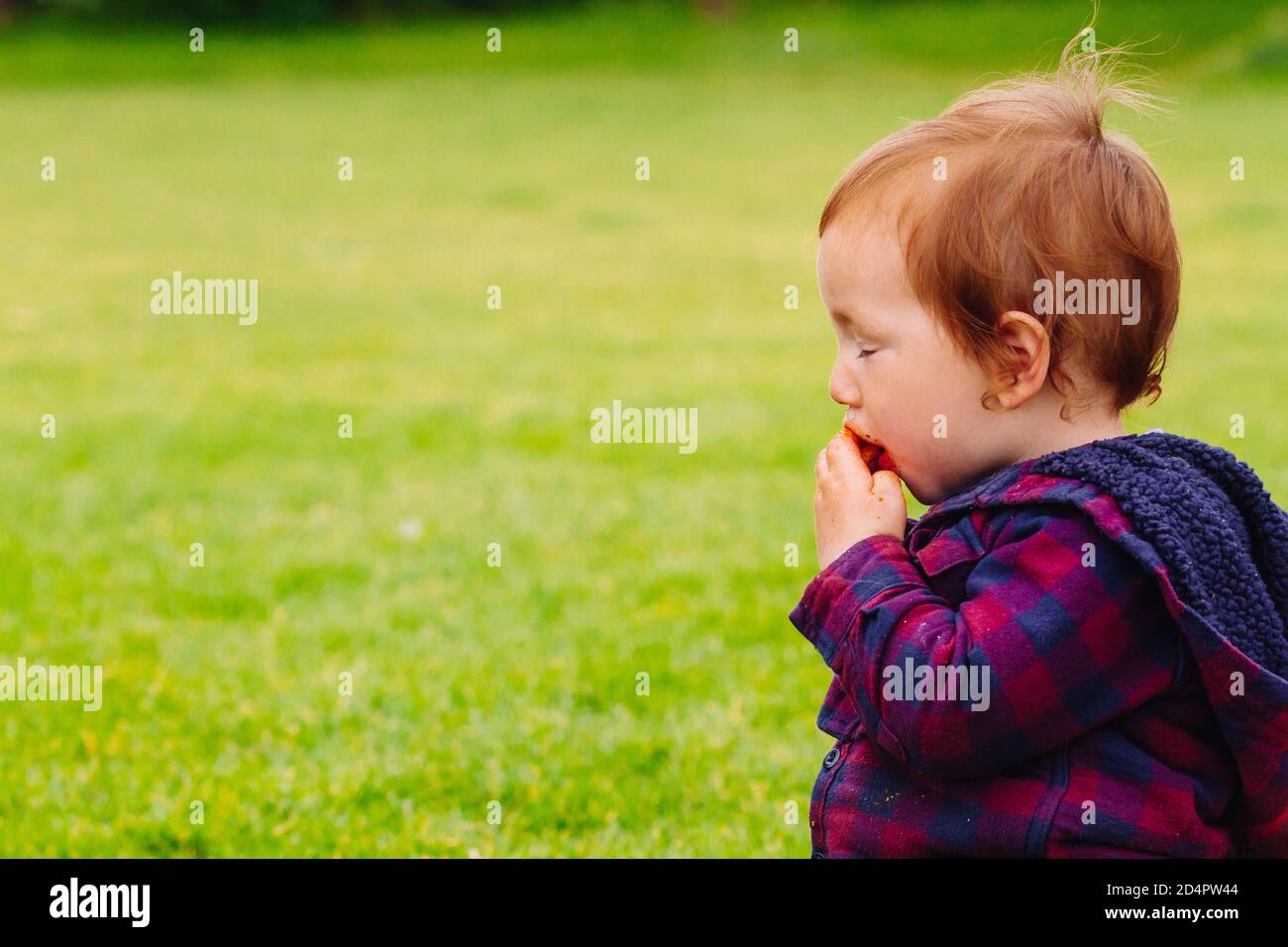 Toddler enjoying a snack outside Stock Photo - Alamy