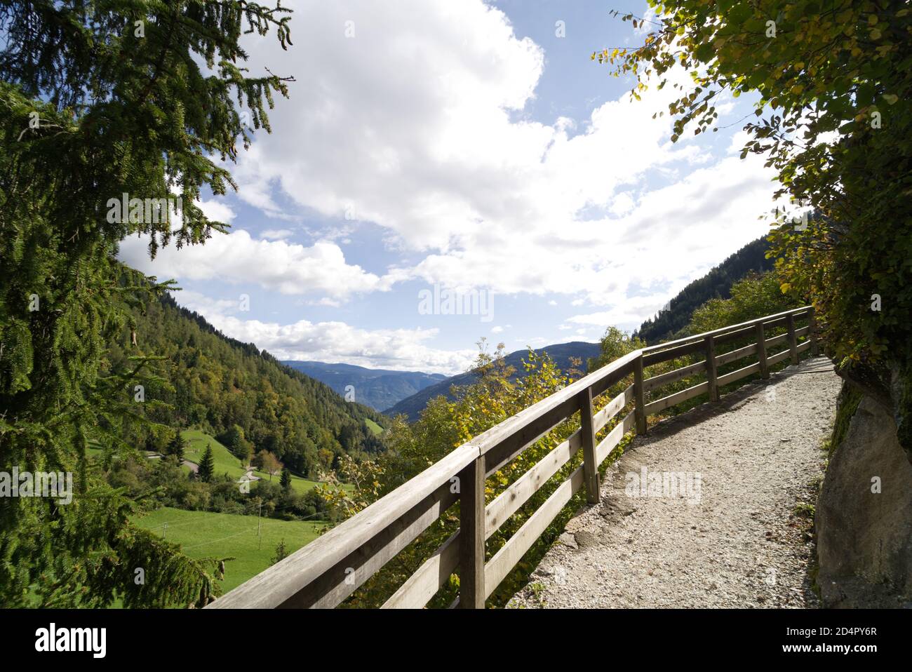 Scenic image of the footpath with wooden rail on the left side and Alps ...