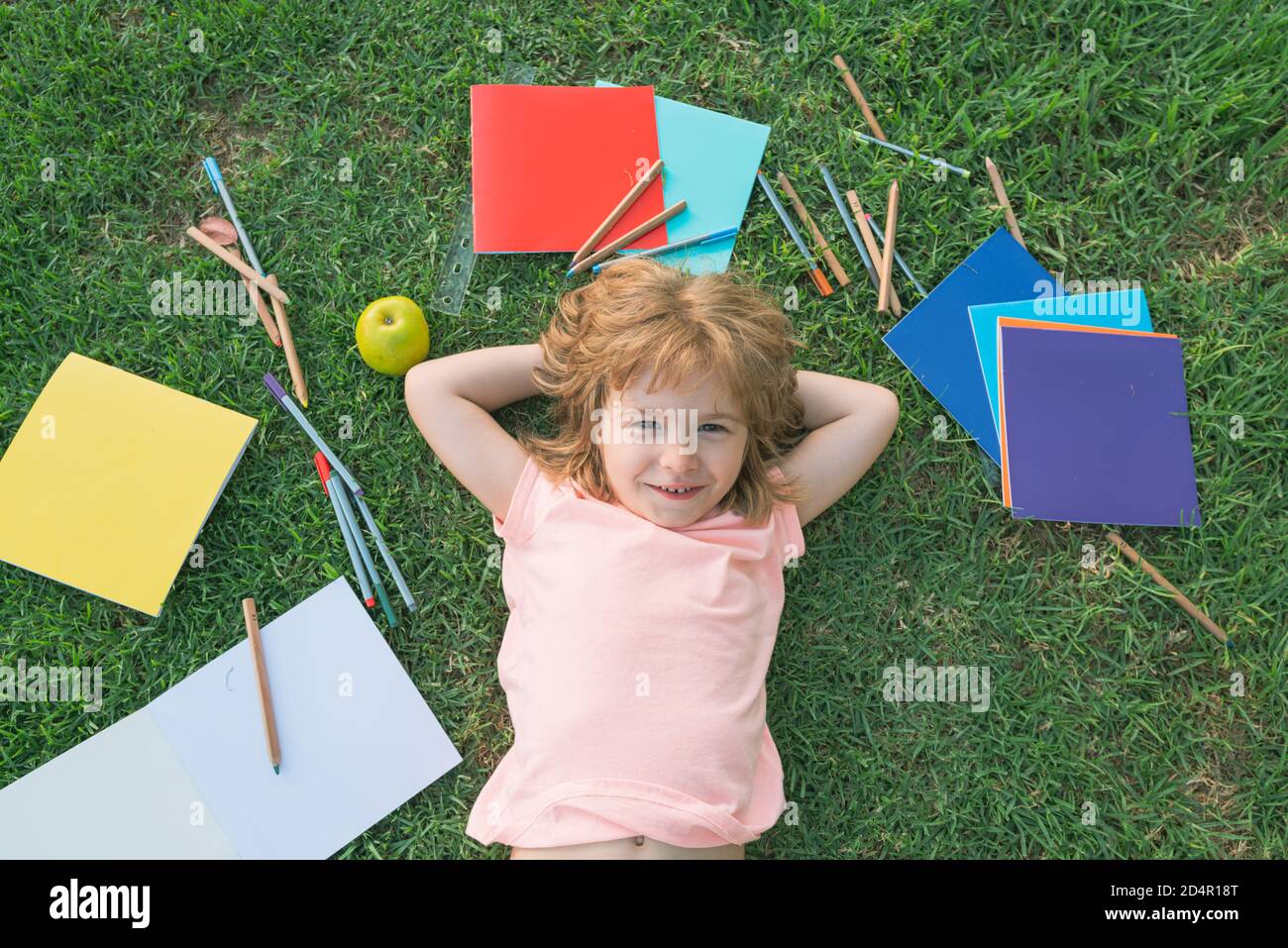 Portrait of cute smart clever school boy nerd doing homework, lie on ...