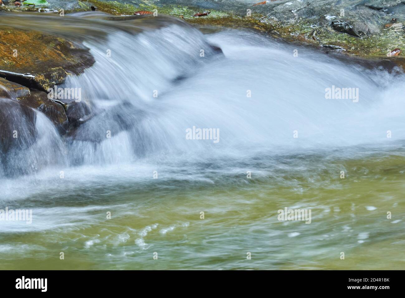 clear stream flows over the stones, forming a small waterfall, water ...