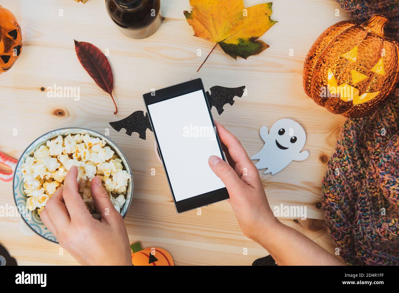 Top view female hand holding smart phone decorated with bat wings with ...