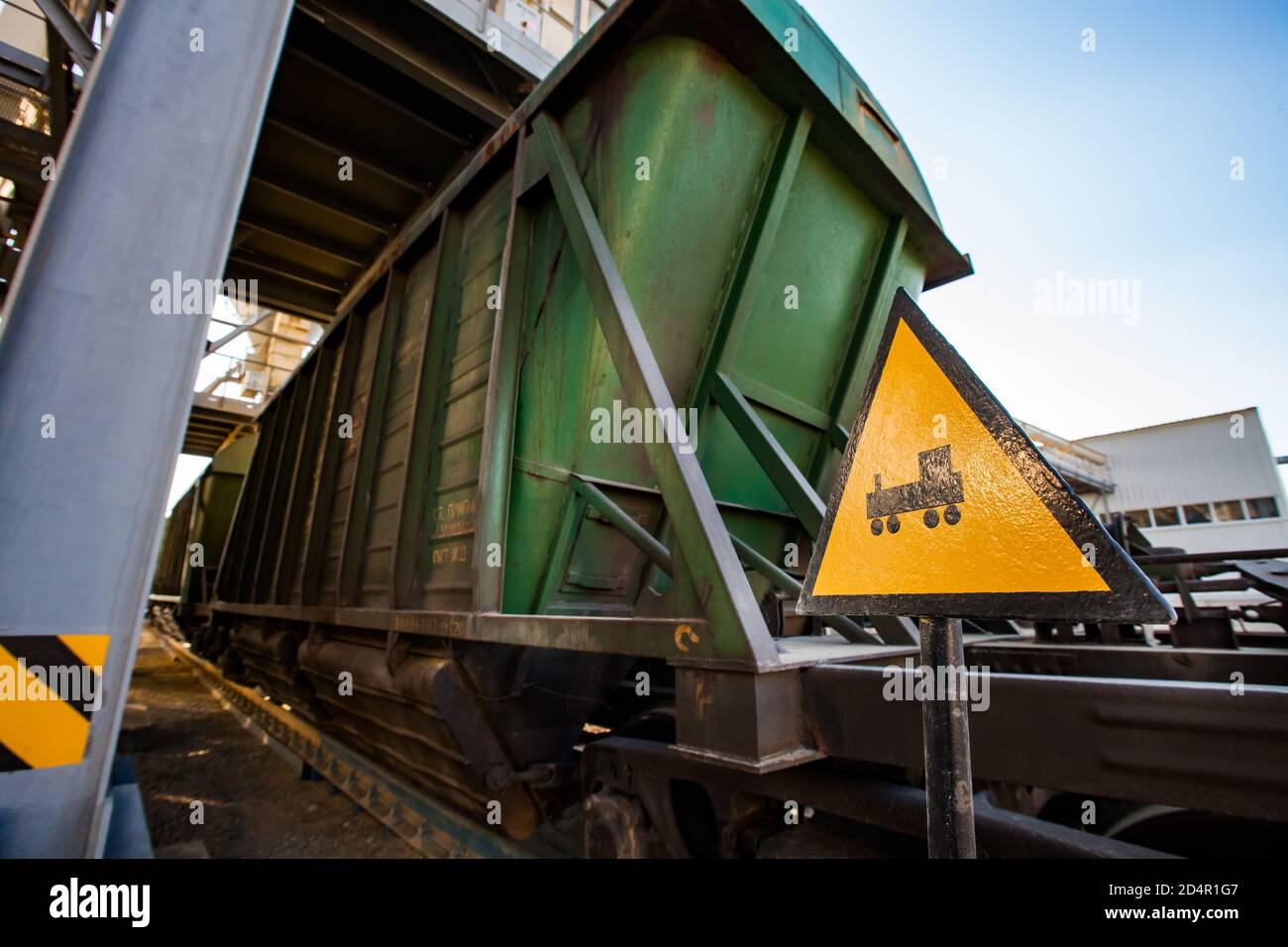 Handmade yellow "Train" road sign. Focus on foreground. Green hopper ...