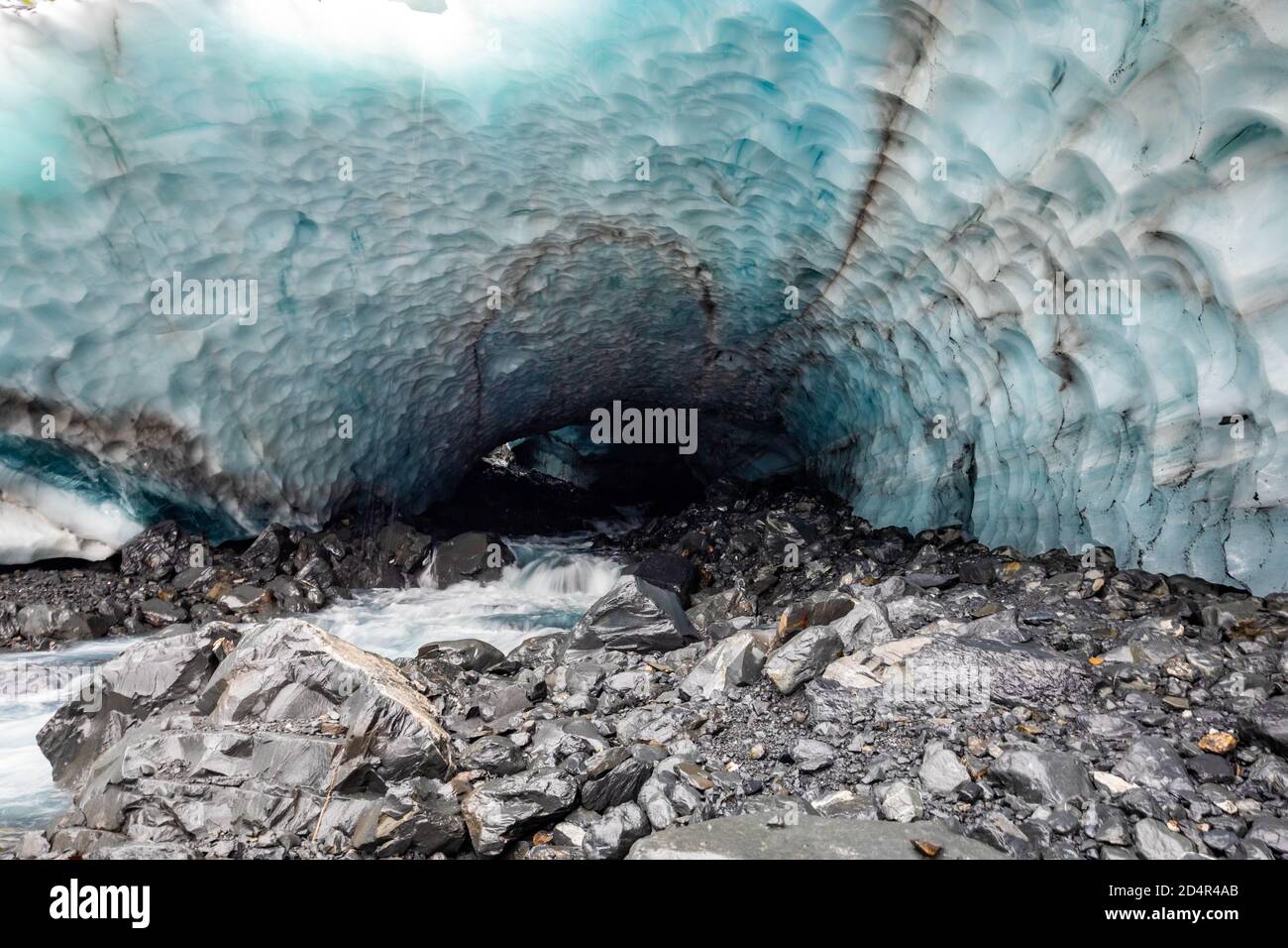 Scenic glacier ice caves with river flowing out from inside nobody ...