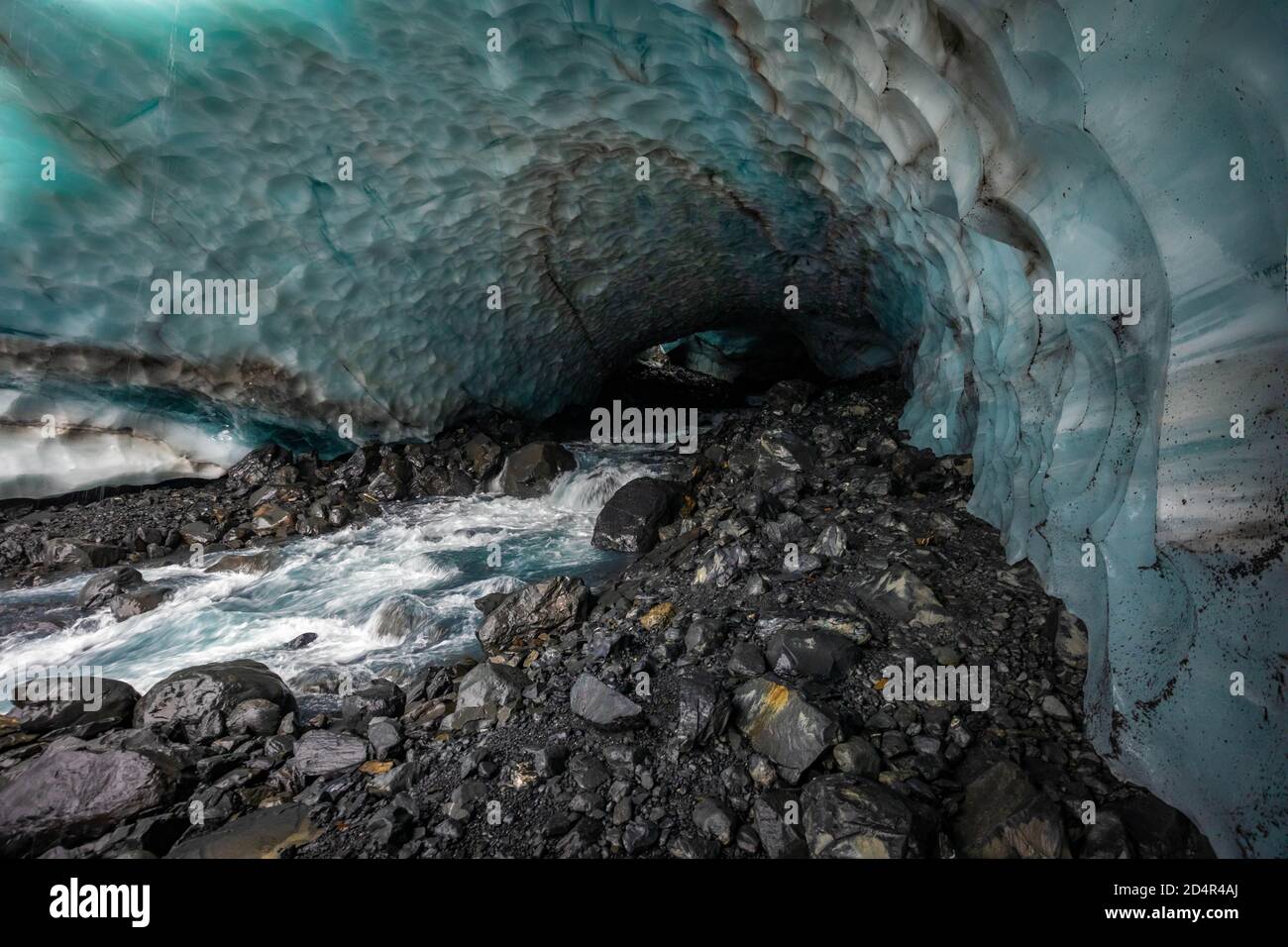Scenic glacier ice caves with river flowing out from inside nobody ...