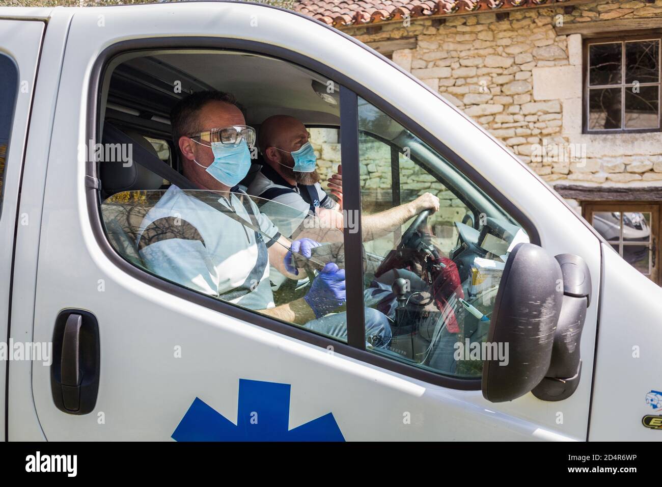 Ambulance drivers in front of the home of a patient with suspected ...