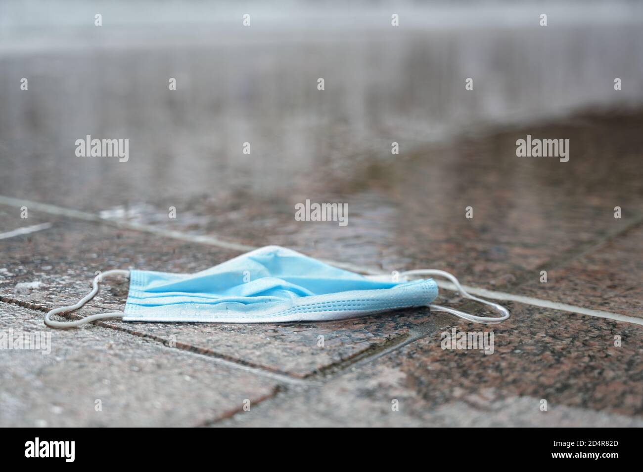 Surgical face mask against covid-19 lying in the rain on the street ...