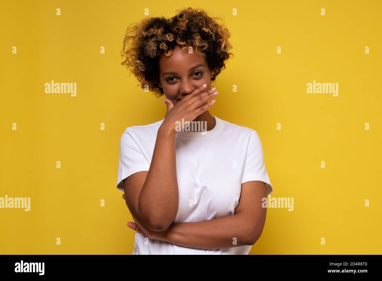 Young african woman giggles covering her mouth with hand, hiding her ...