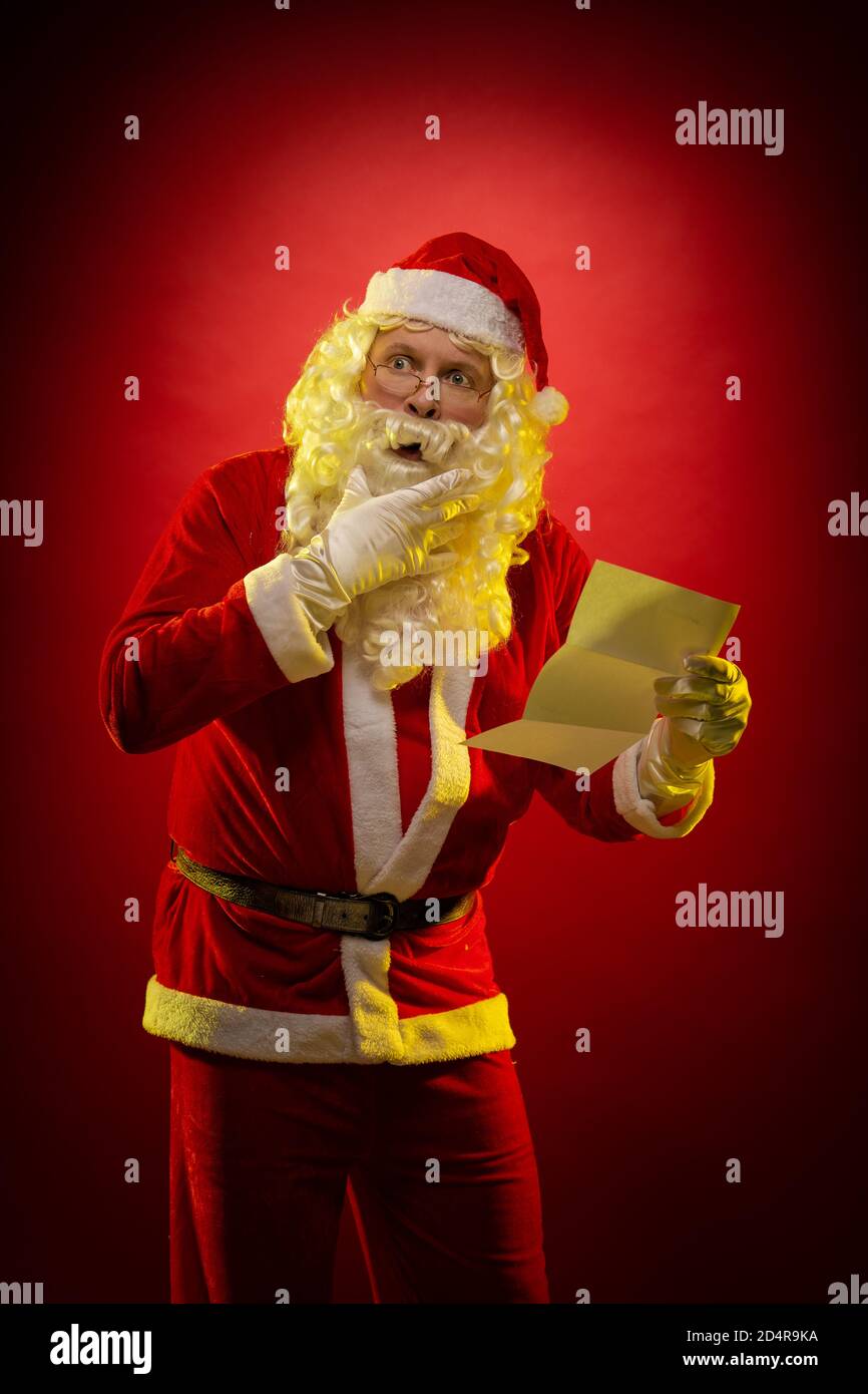 Male actor dressed as Santa Claus holds a sheet of paper in his hands a ...