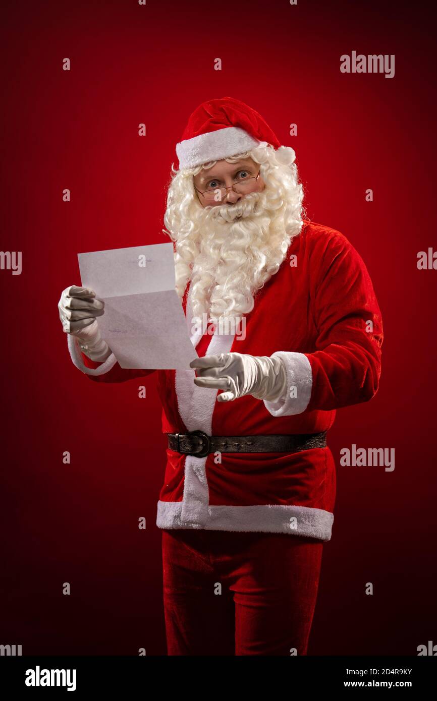 Male actor dressed as Santa Claus holds a sheet of paper in his hands a ...