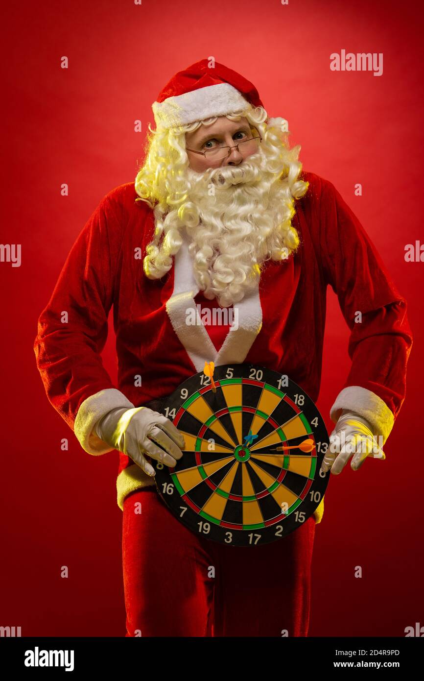 Male actor in a costume of Santa Claus holds a darts target in his ...