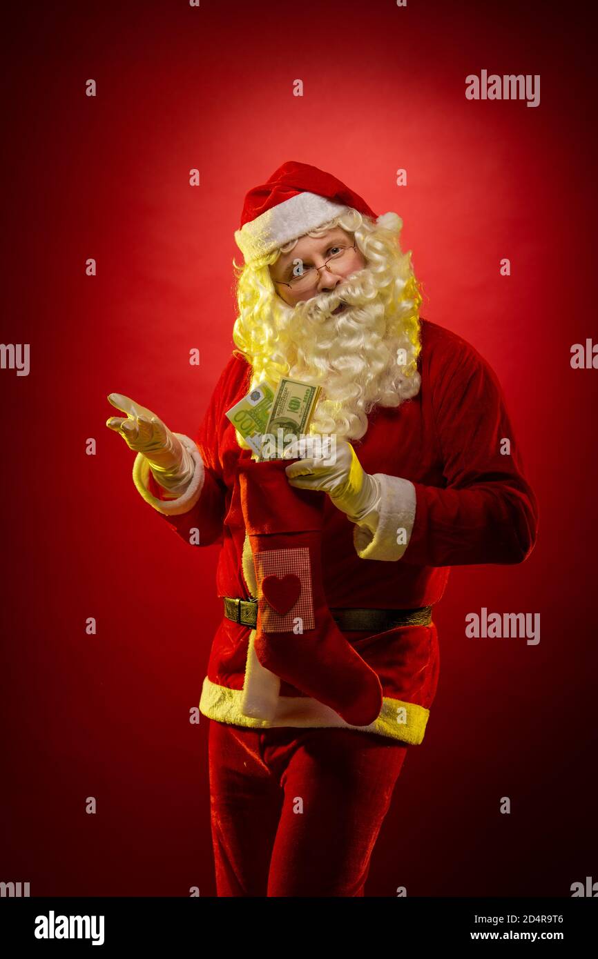 Male actor in a suit of Santa Claus holds in his hands banknotes, money ...