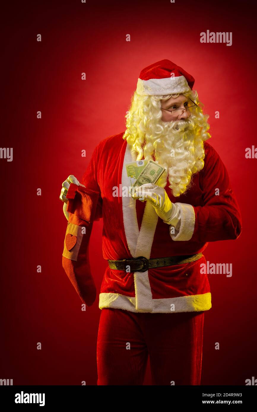 Male actor in a suit of Santa Claus holds in his hands banknotes, money ...