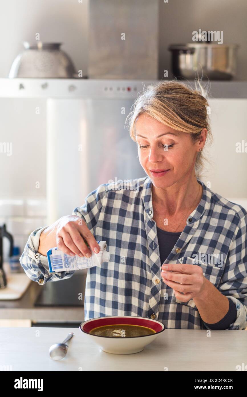 Woman adding fresh cream to a soup Stock Photo - Alamy