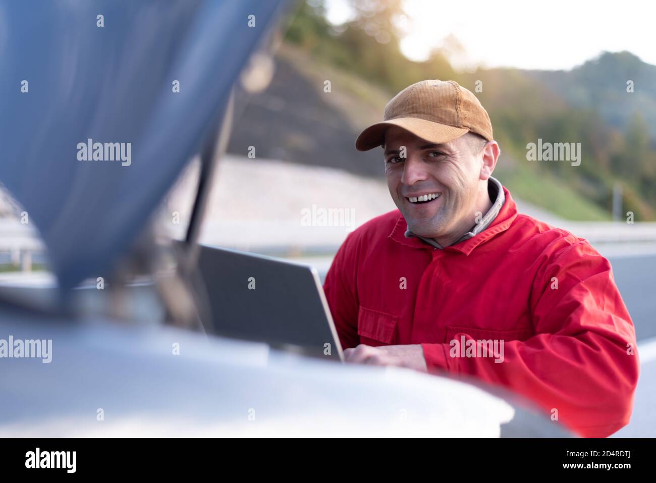 Handsome auto mechanic or road assistance worker in uniform repairing ...