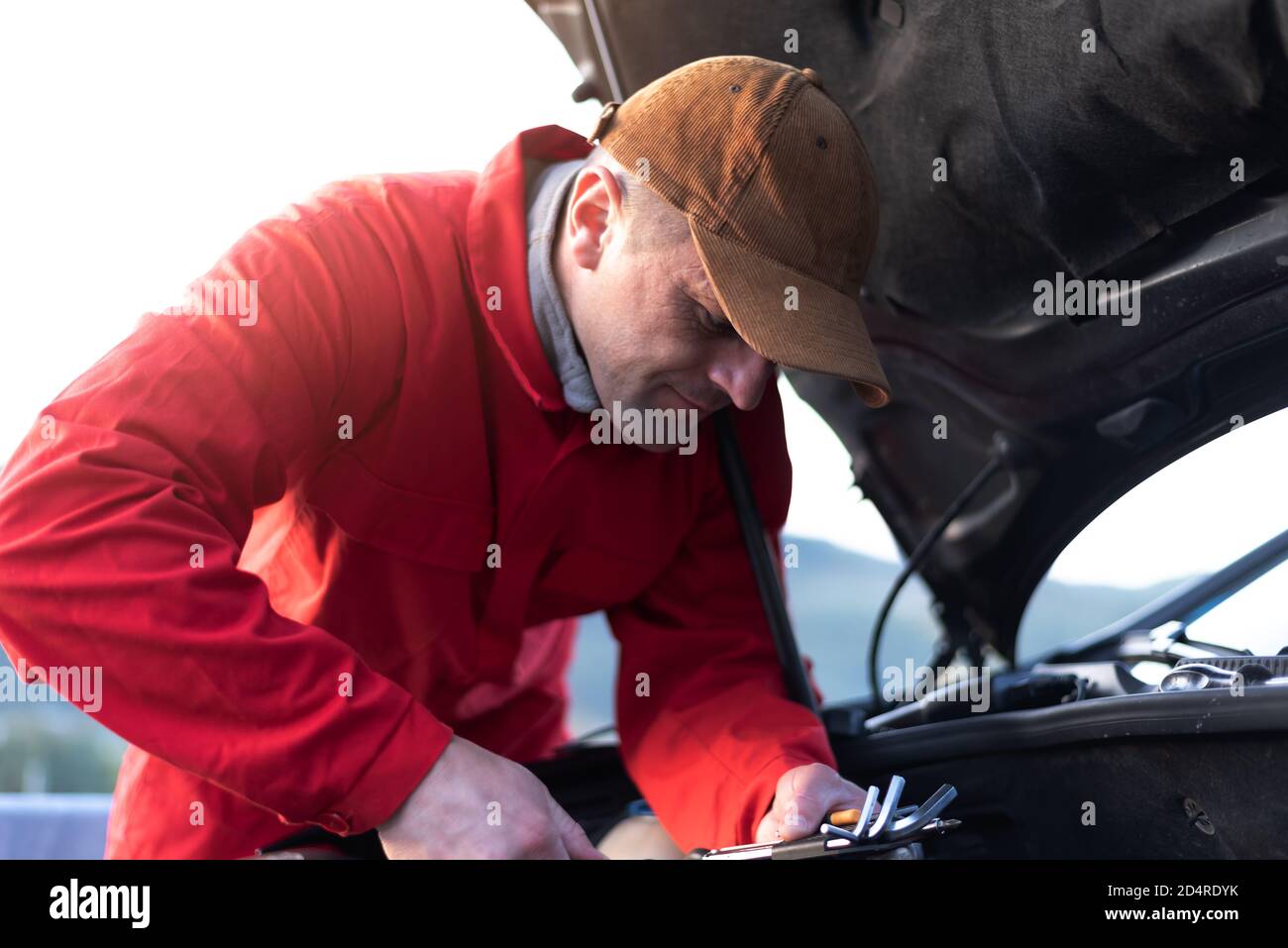 Handsome auto mechanic or road assistance worker in uniform repairing ...