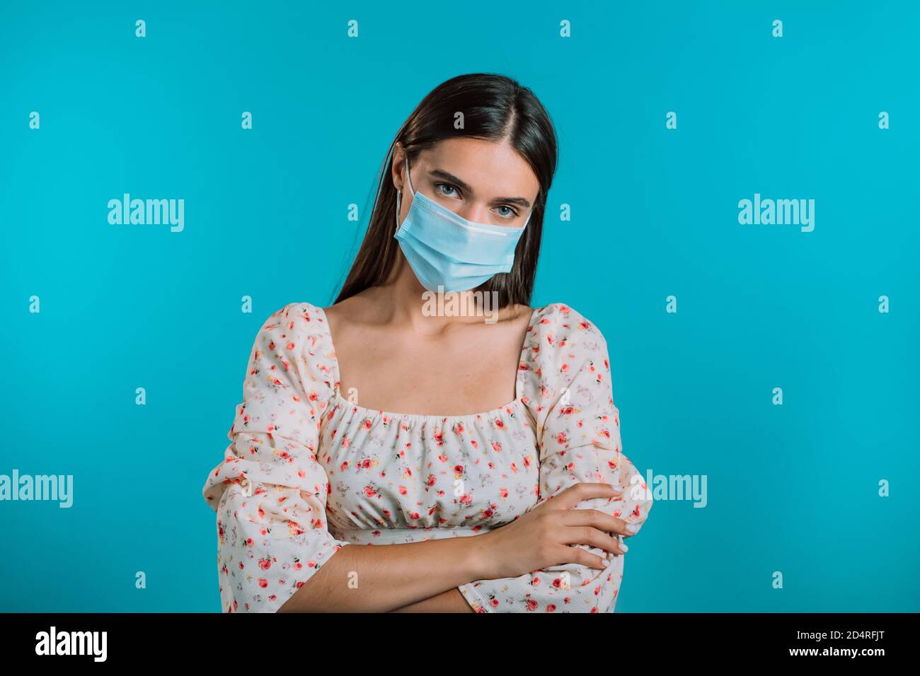 Angry annoyed woman in medical mask keeping arms crossed and staring at ...