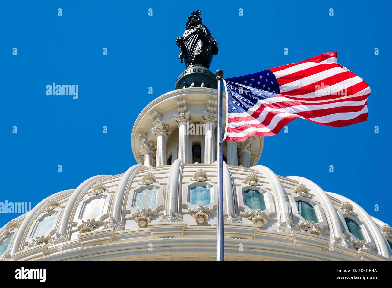The United States flag waving in front of the Capitol dome in ...