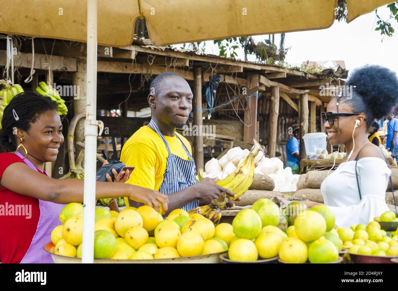 Young beautiful African customer making transaction with two African ...